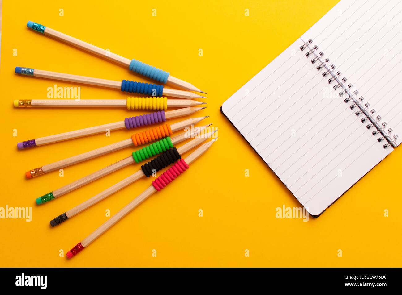 A top view of an open journal and pencils with colorful rubbers ...
