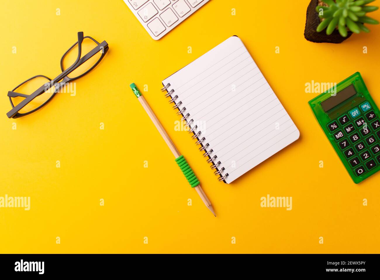 A top view of a journal, calculator, pencil, glasses, keyboard, and a ...