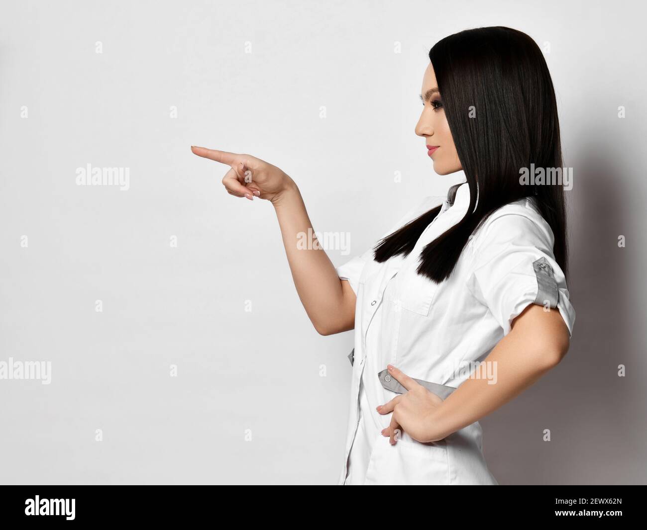 Young pretty woman doctor nurse in medical gown stands sideways to ...