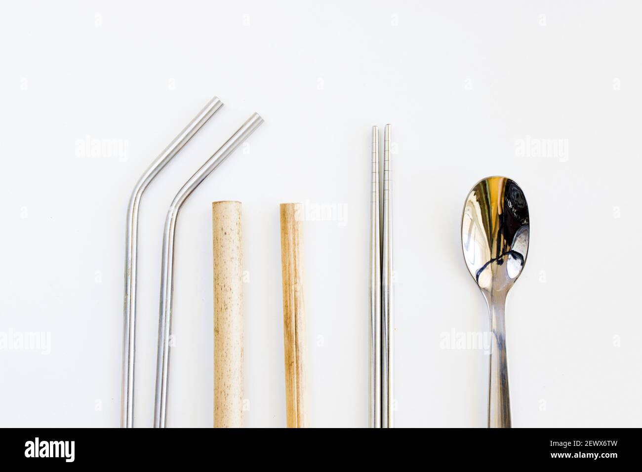 A top view of a bamboo and metal straw, spoon and chopsticks on the ...