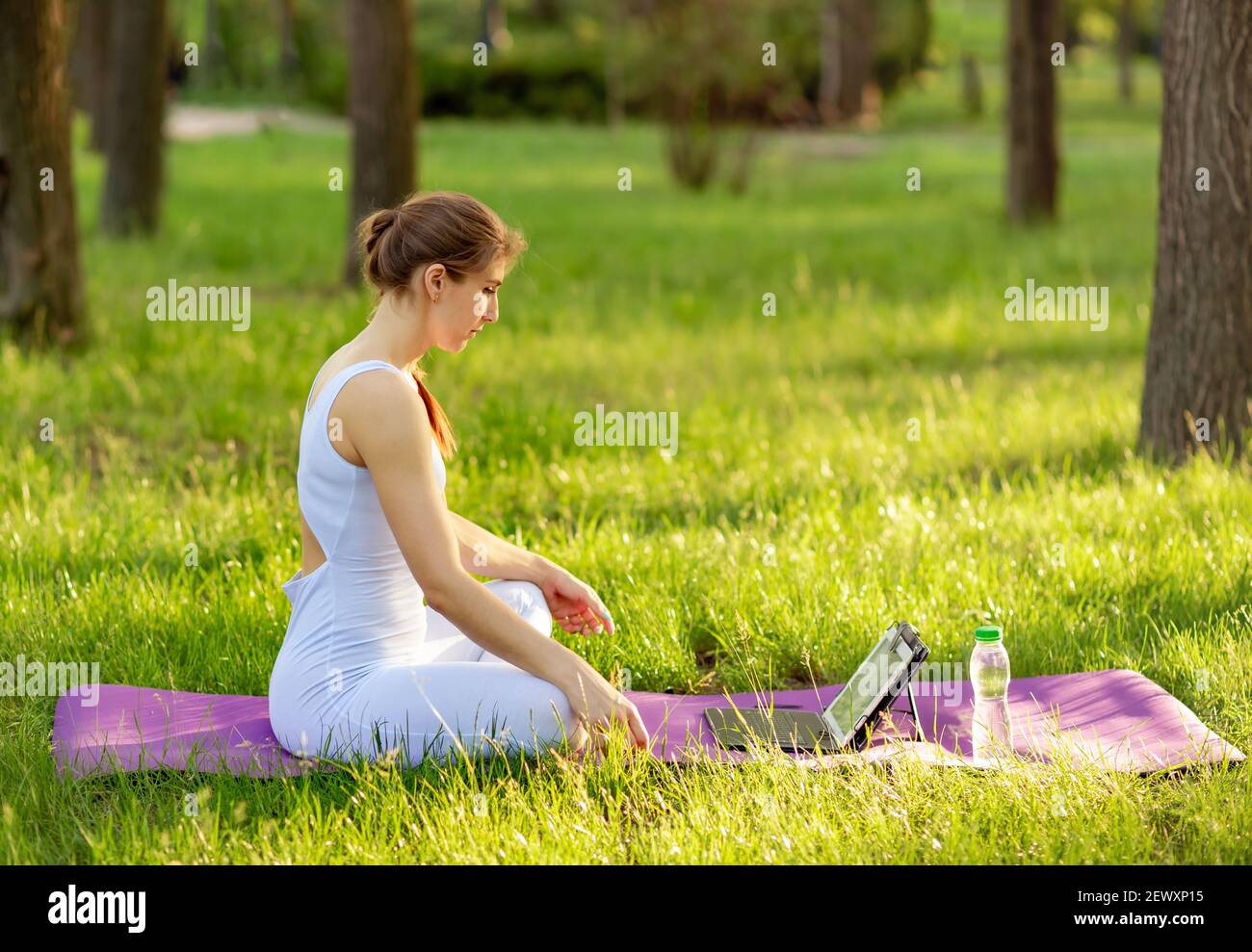 Happy sportswoman exercising and watching online exercise on laptop ...