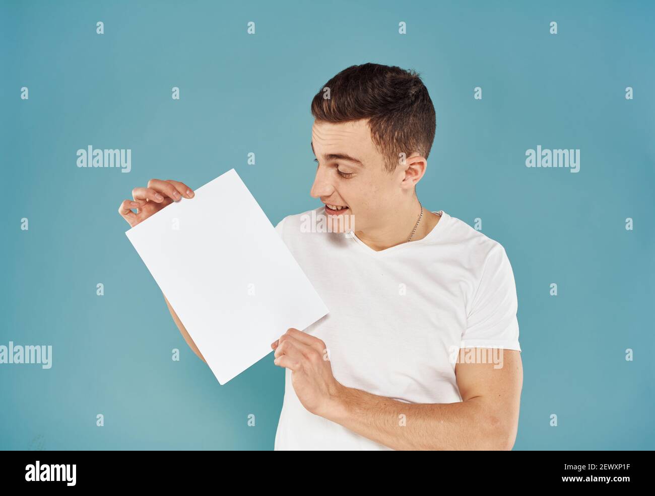 Male advertiser with a white sheet of paper on a blue background mockup ...