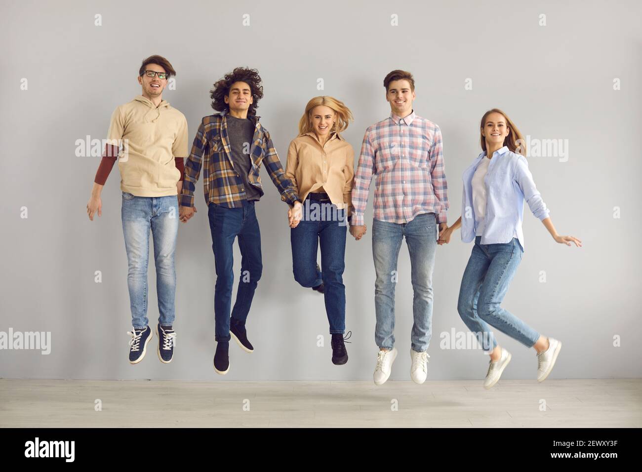 Group of cheerful school, college or university friends jumping for joy ...