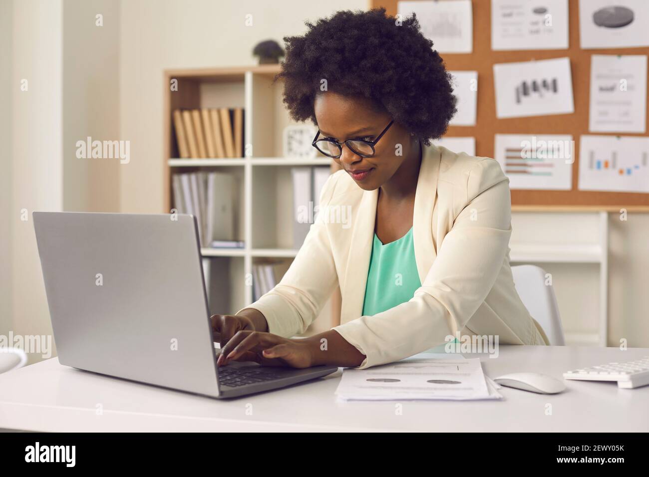 African american woman sitting at desk in office, working on laptop ...
