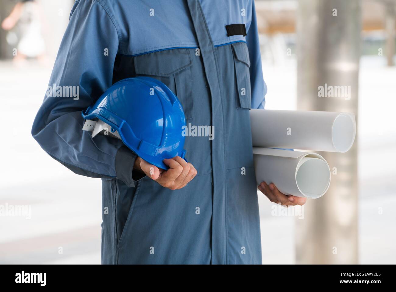 Engineer on professional wear holding hard hat and blueprint drawing ...