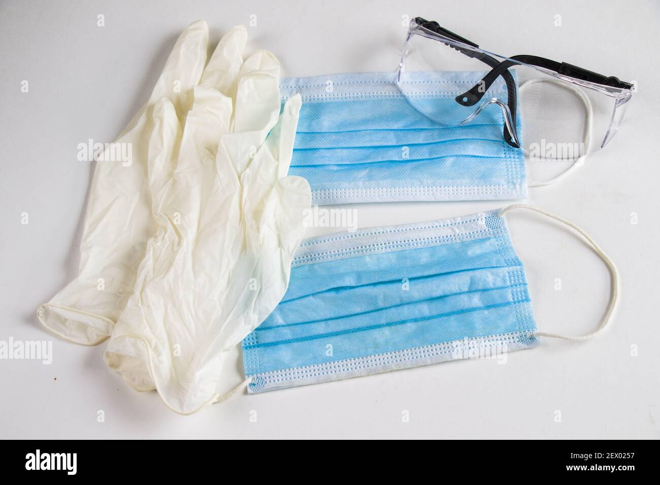 Surgical face masks, gloves, and safety glasses isolated on a white ...