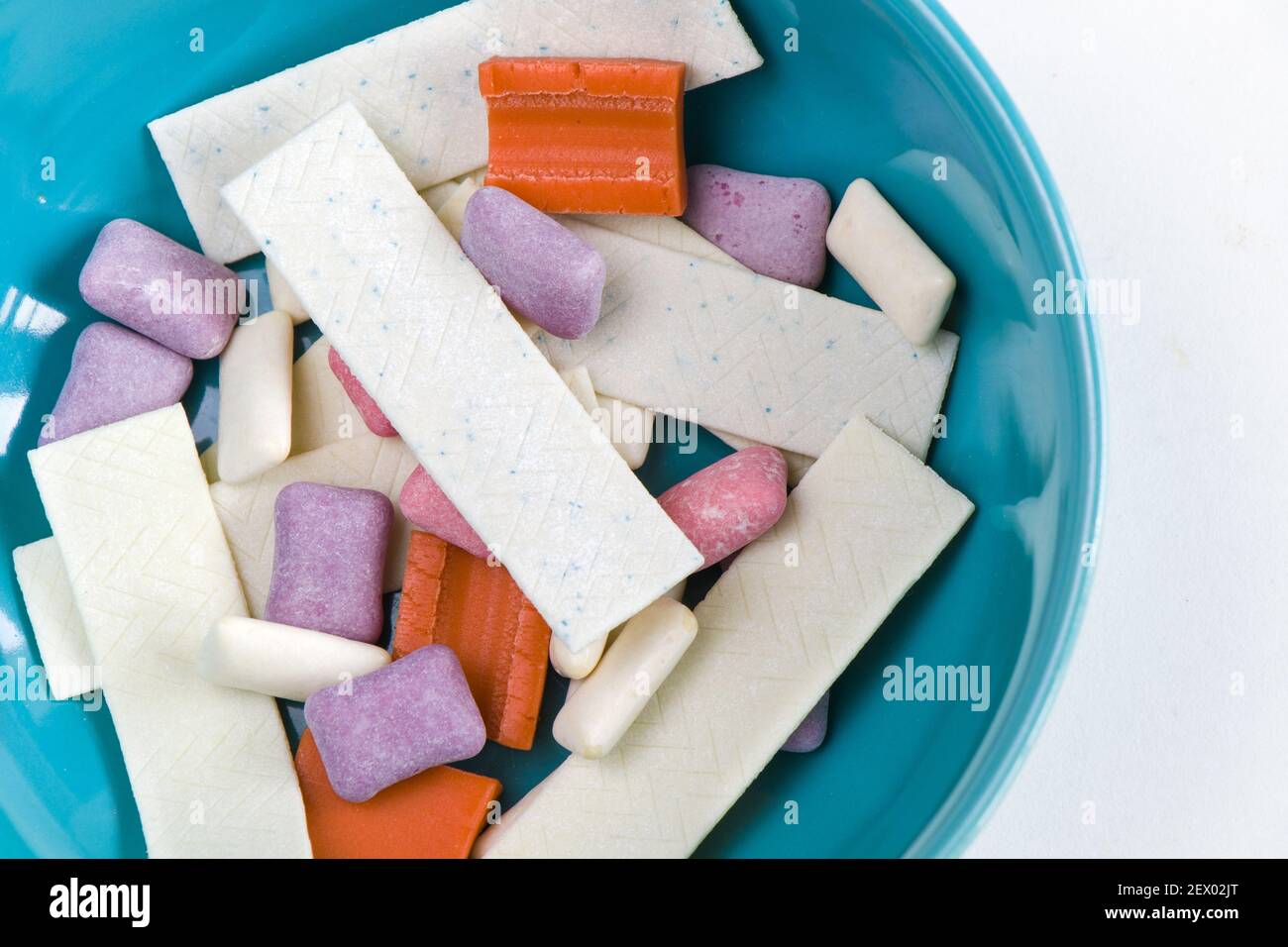 Different chewing gums in a blue bowk isolated on a white background ...