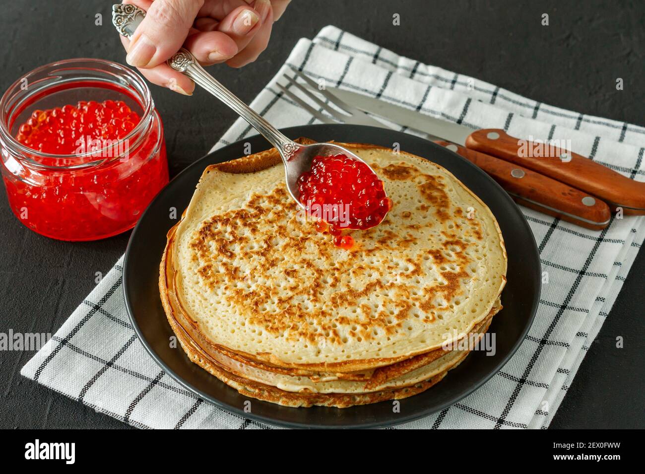 Traditional Russian Crepes Blini stacked in a plate with red caviar on ...