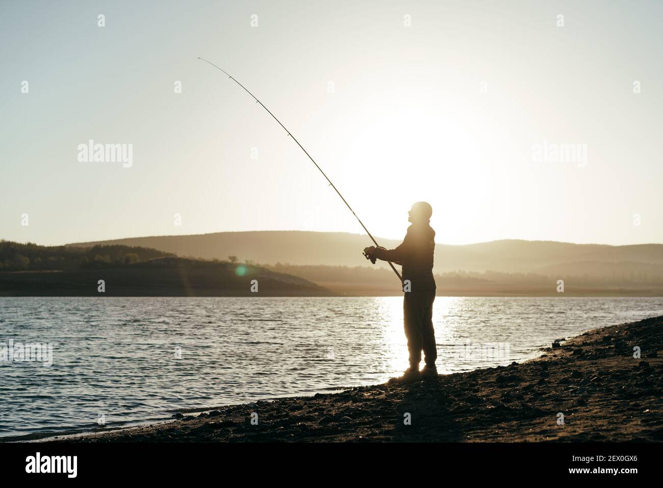 Fisherman with rod fishing on the lake Stock Photo - Alamy