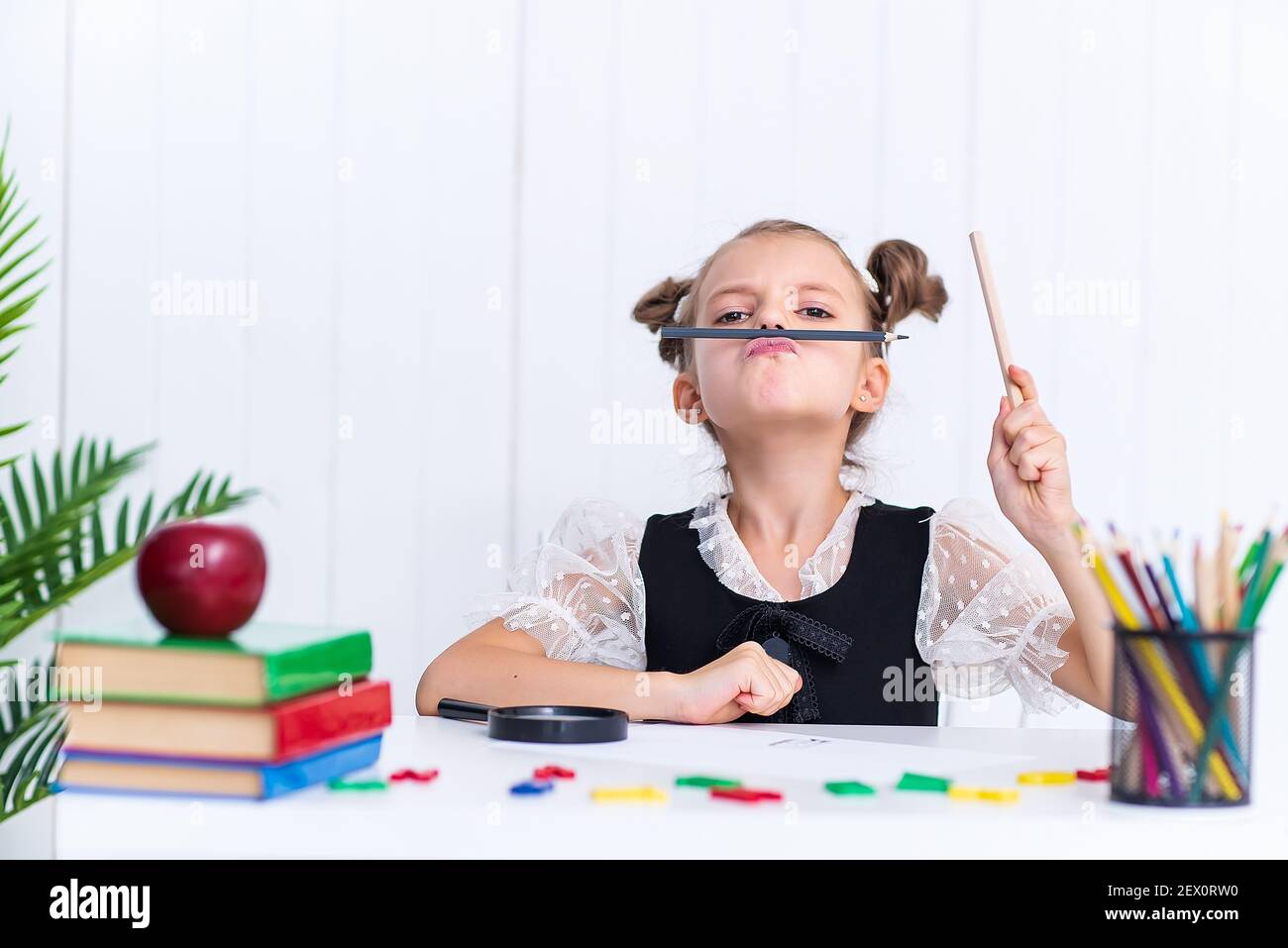 Happy smiling pupil at the desk. Child in the class room with pencils ...