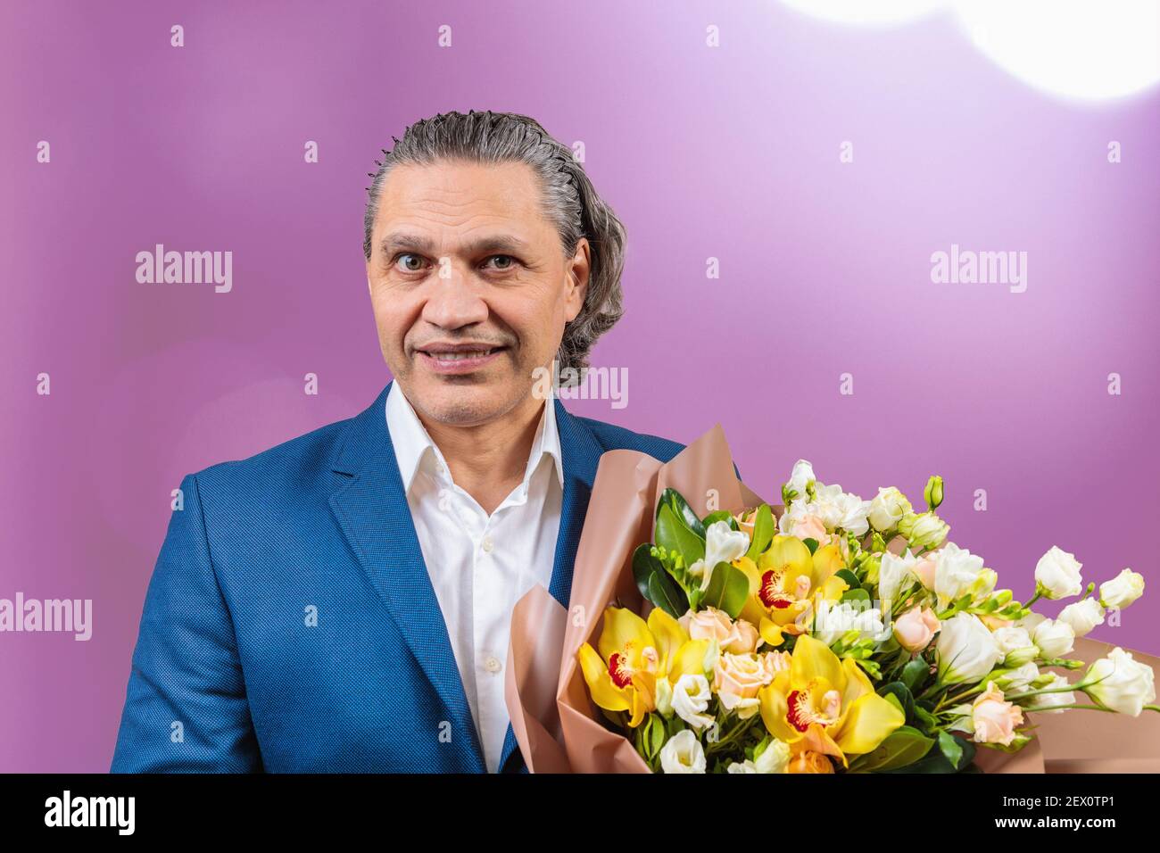 Smiling 50-year-old man in a blue jacket with a bouquet of flowers on a ...