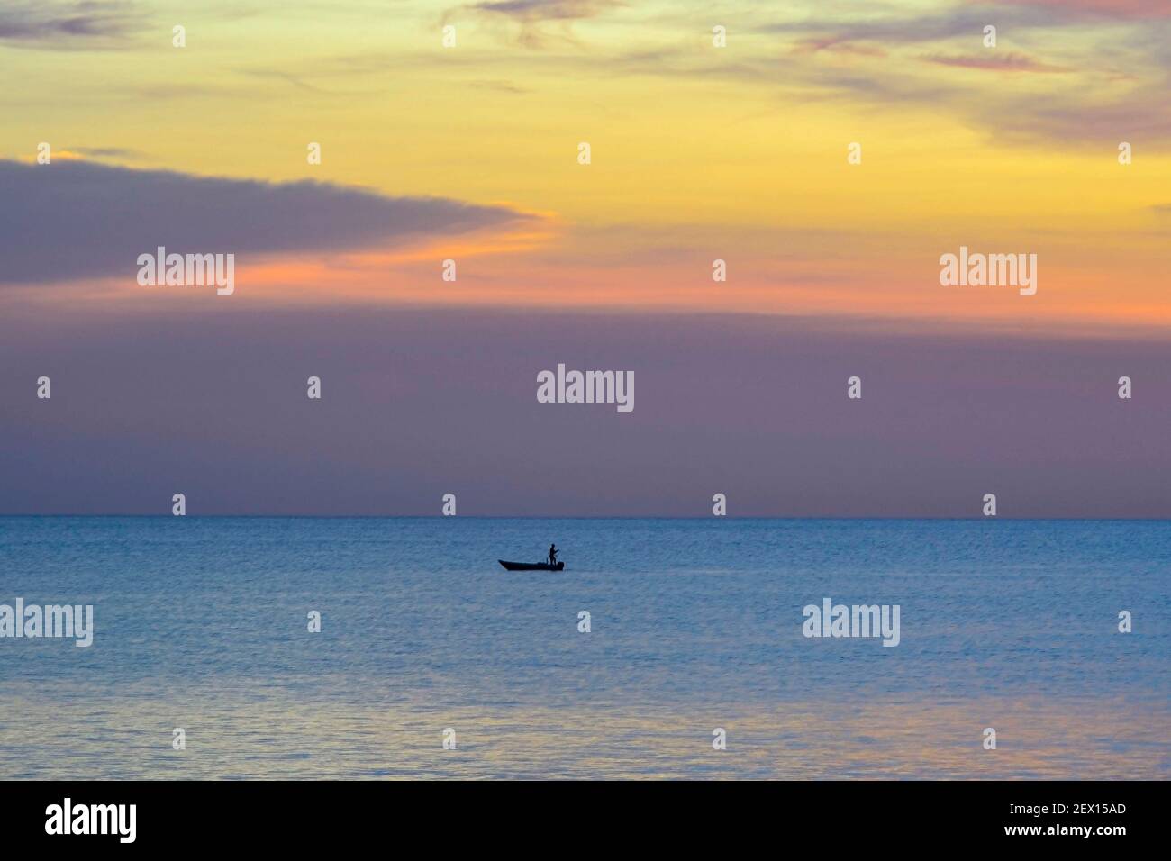 Evening Sunset At The Beach And Fisherman Fishing From Afar Stock Photo ...
