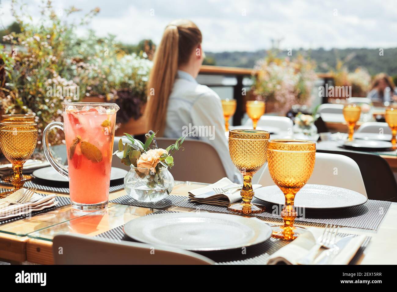 Lemonade with oranges in jug with ice bucket on white table in ...