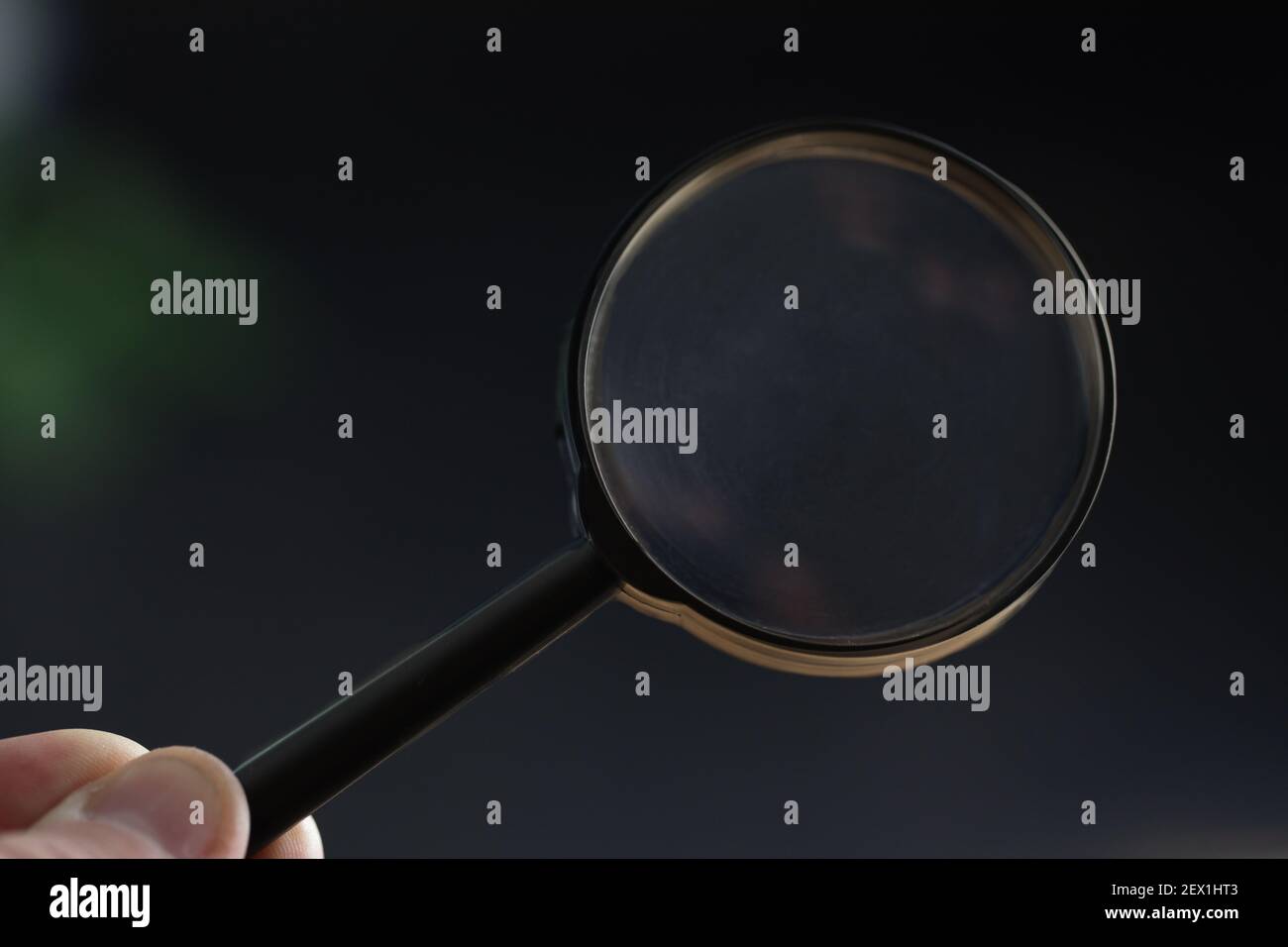 hand holding magnifying glass in dark room. concept of uncovering ...