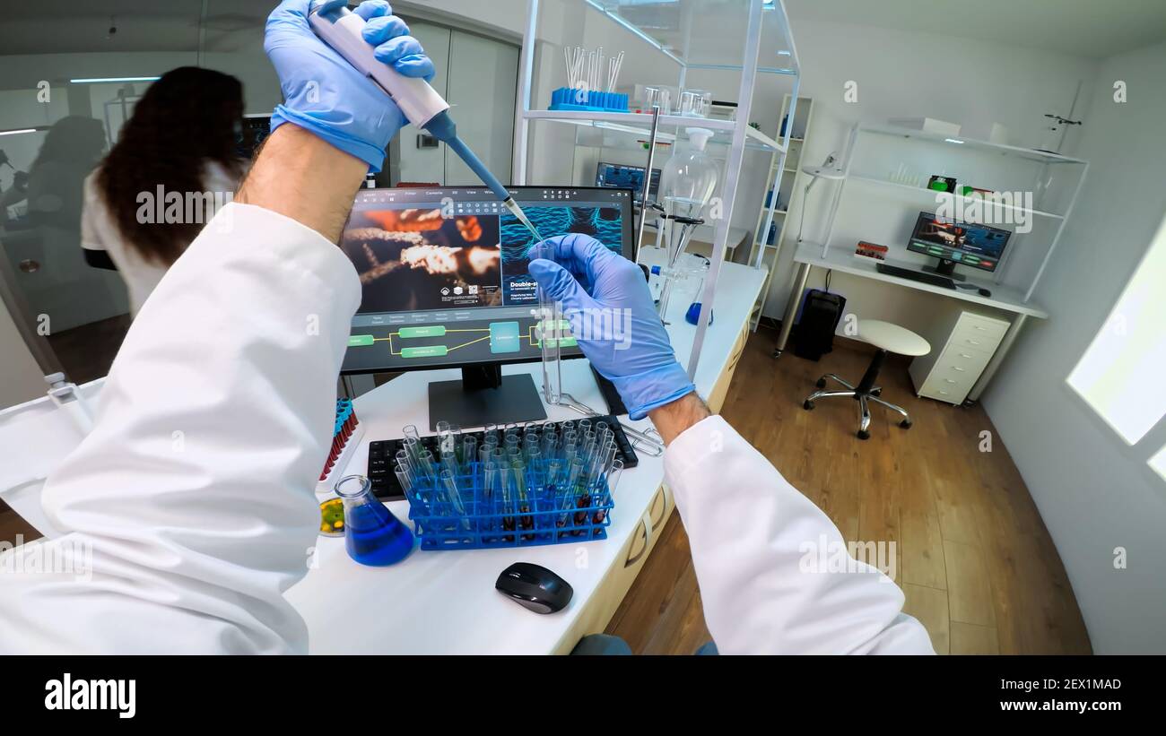 POV of scientist using micropipette in lab to extract blue liquide from ...