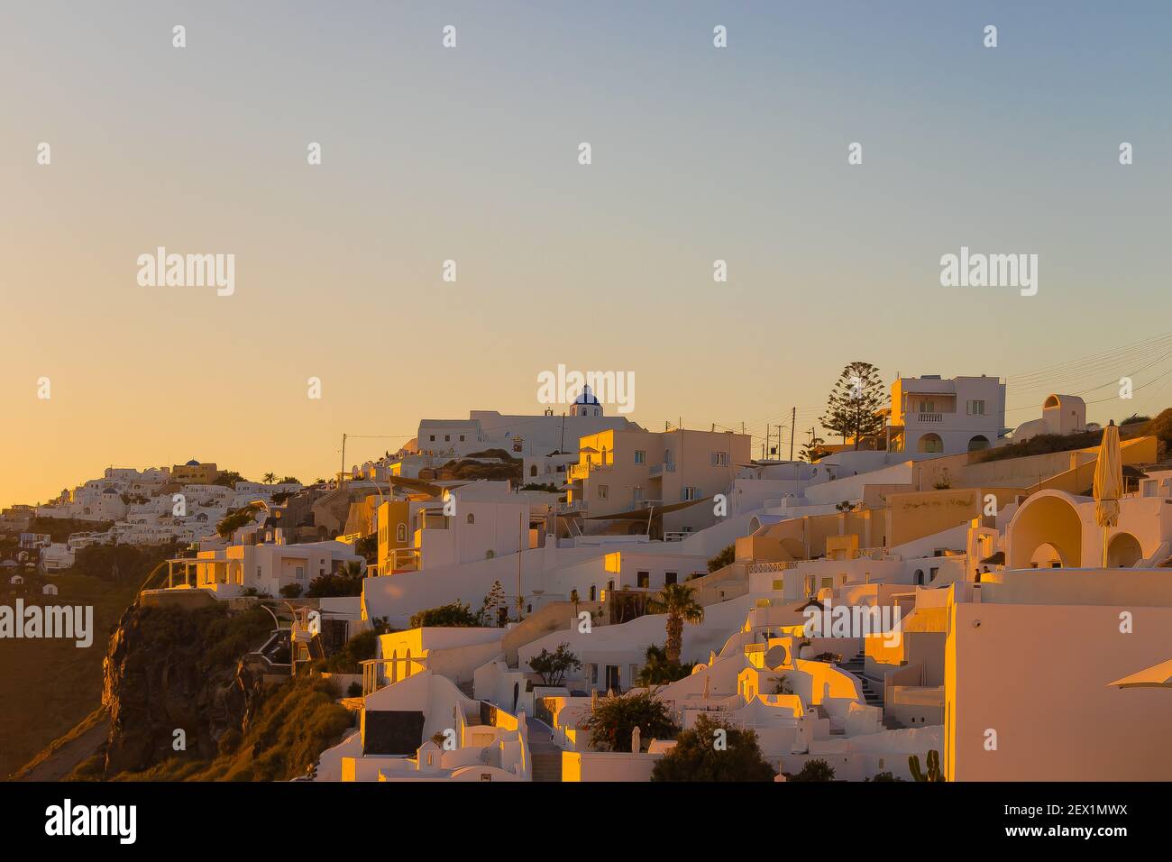 A scenic view of the old town in Santorini, Greece under a sunset sky ...