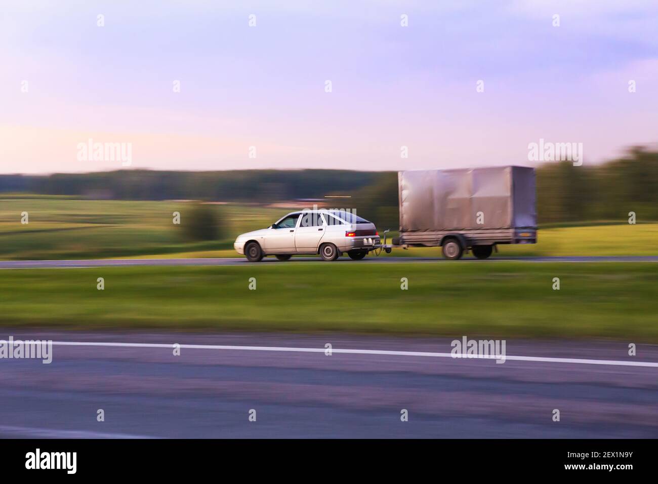 car with trailer moves on highway in evening Stock Photo - Alamy