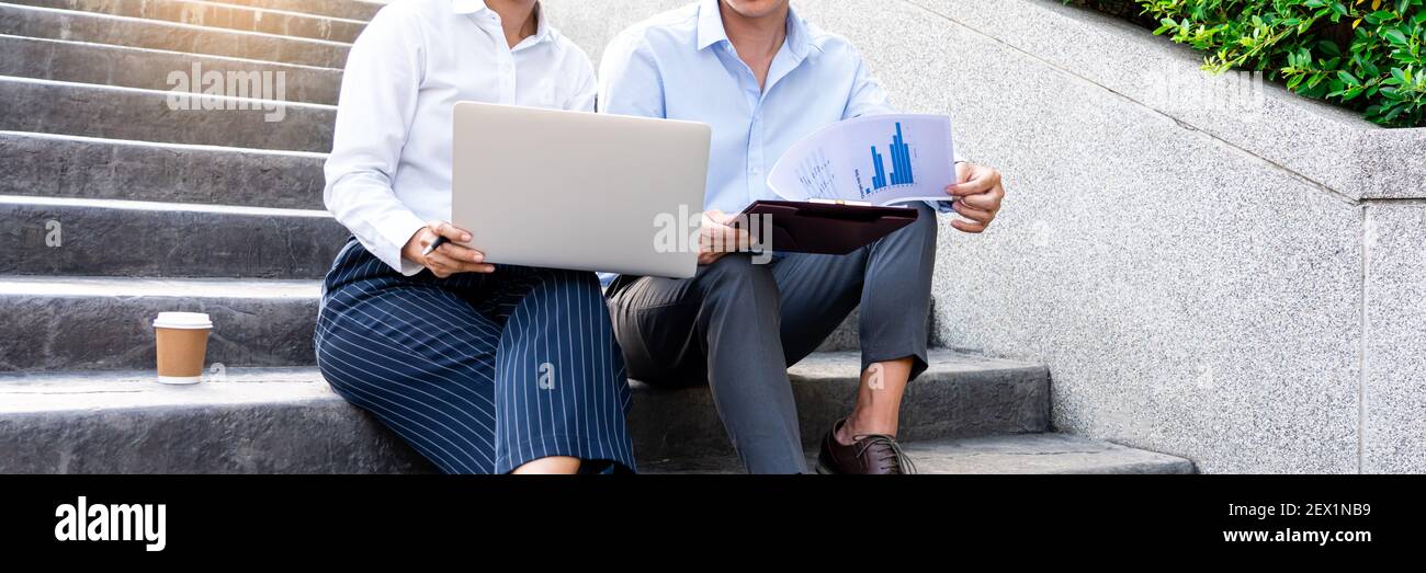 Two asian business coworkers outside office buildings discuss and ...