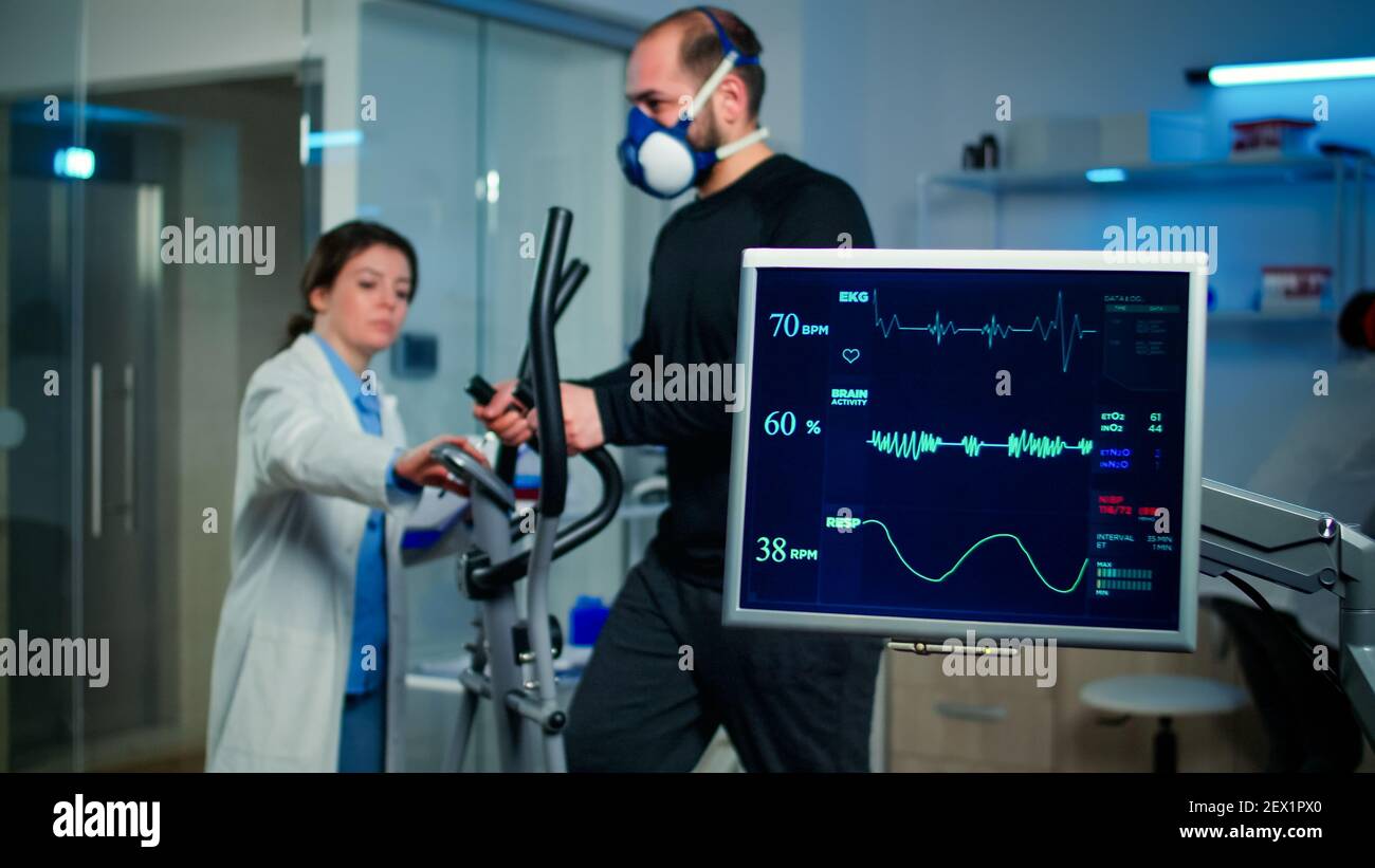 Monitor shows EKG reading of man athlete running on cross trainer and ...