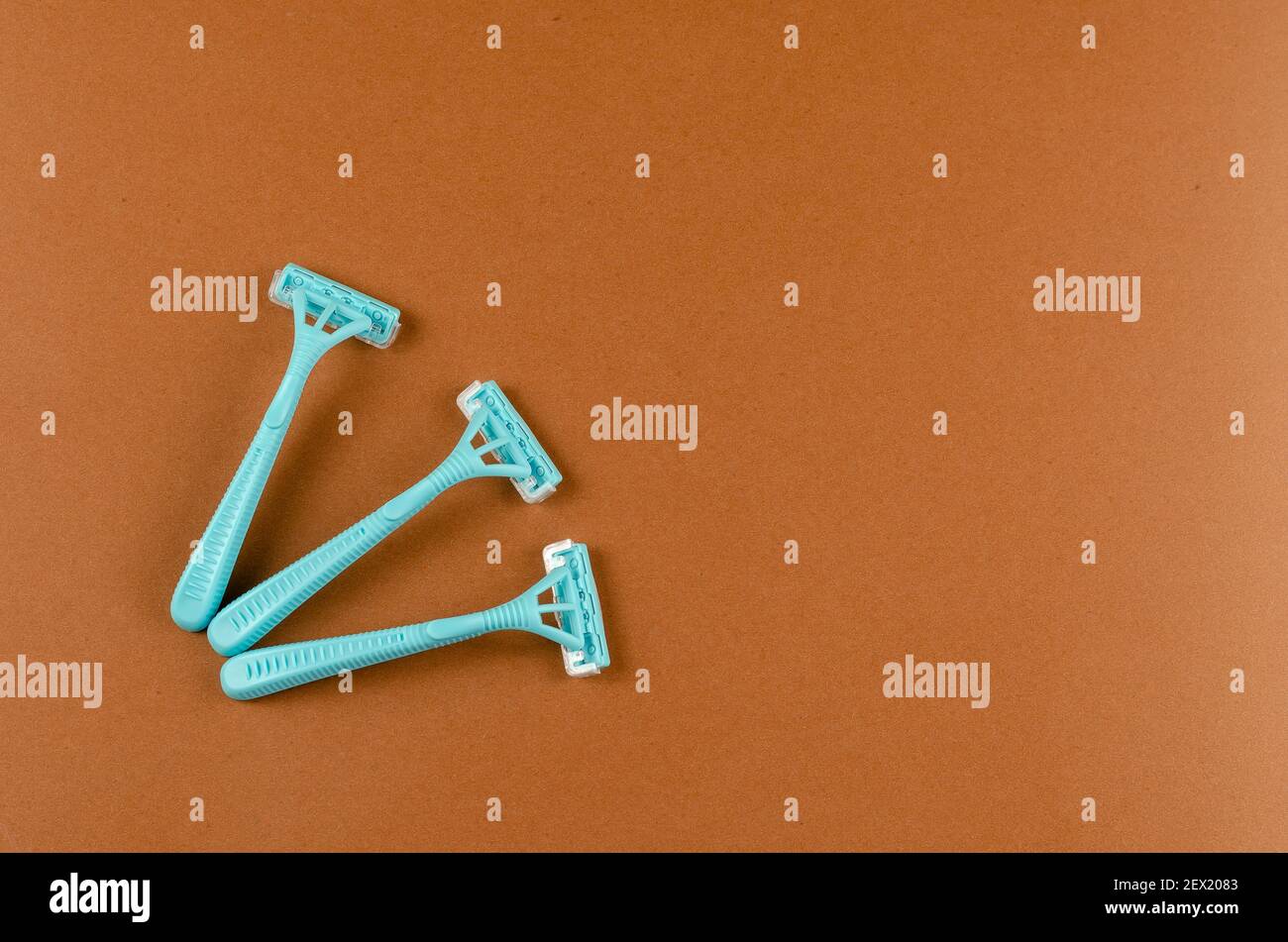 Blue plastic razors on a brown background. Three new razor. Top view ...