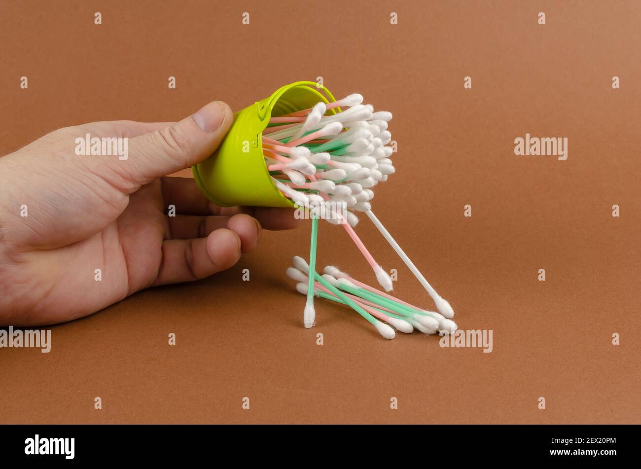 xuSmall bucket, cotton swabs and a hand on a brown background. A man's ...