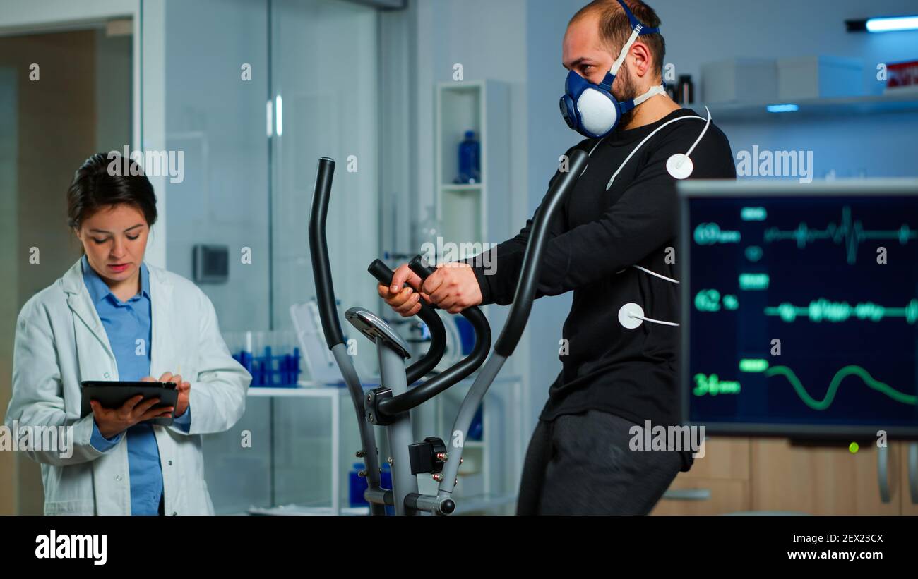 Monitor showing EKG reading of athlete running on cross trainer, while ...