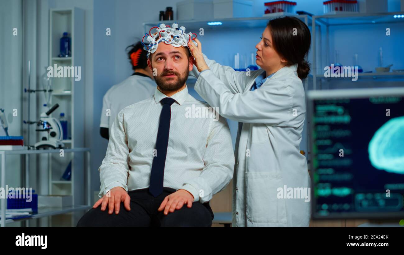 Woman researcher putting brainwave scanning headset to patient ...
