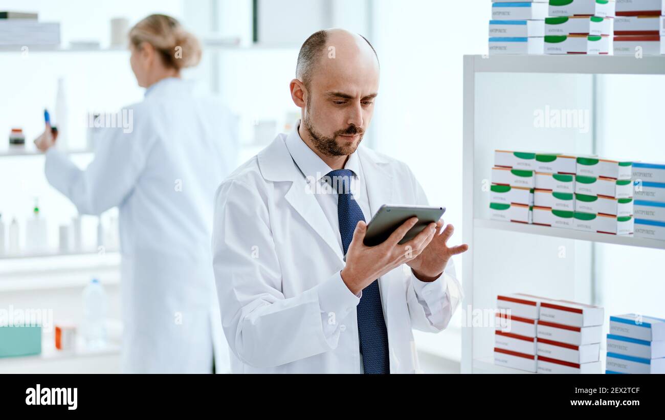 pharmacist with a digital tablet standing near a display case with ...