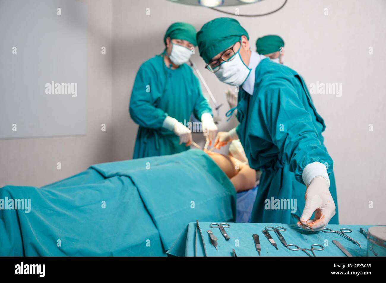 Asian team surgeon choosing scalpel while operating seriously injured ...