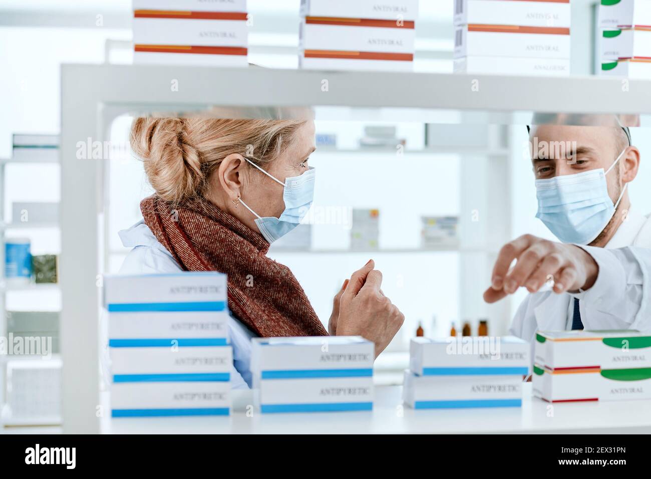 pharmacist and a customer in protective masks are talking near a ...