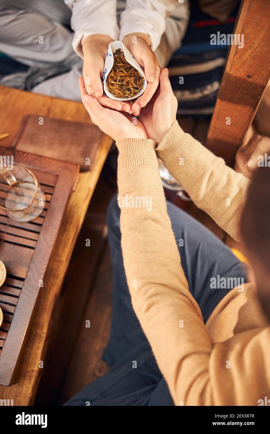 Young woman giving bowl of tea leaves to friend in cafe Stock Photo - Alamy
