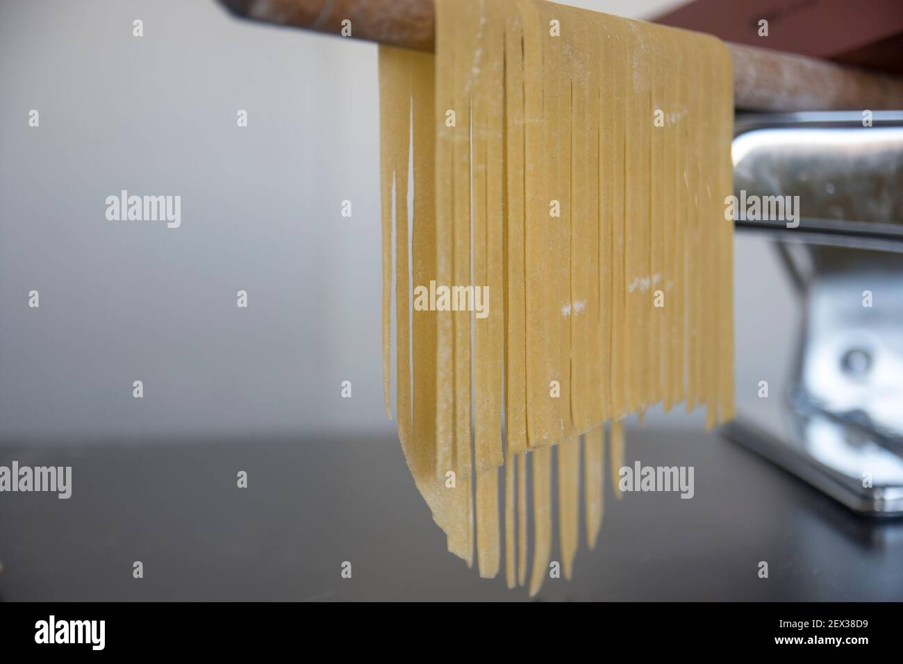 Homemade pasta linguine hanging on wooden stick to dry. Homemade ...