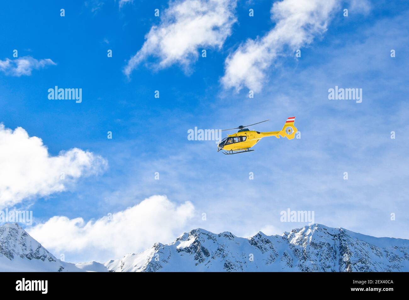 A yellow rescue helicopter flies over the snowy Alps Stock Photo - Alamy