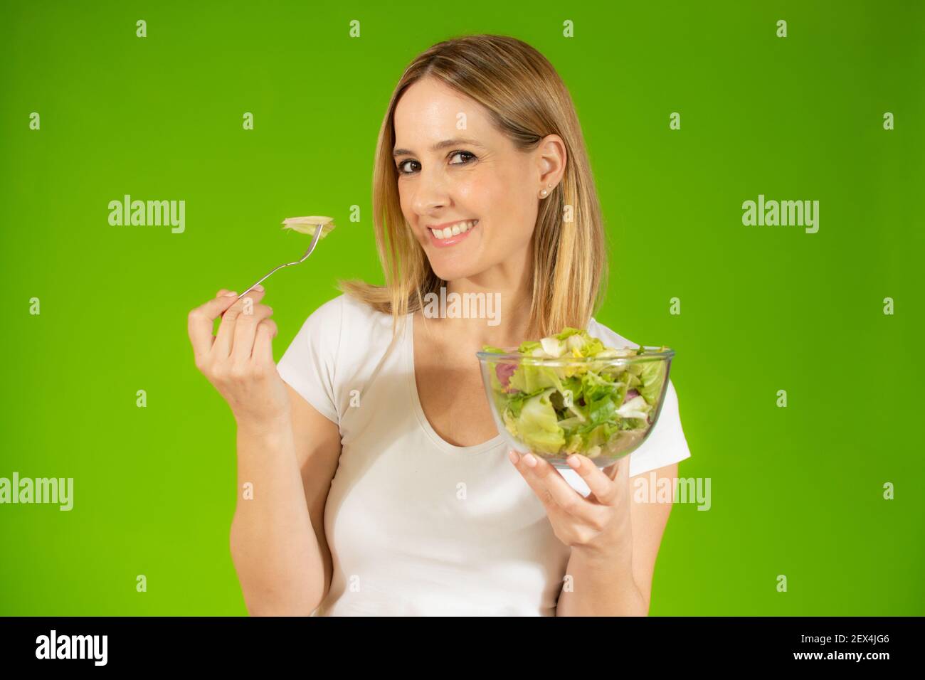Woman diet concept portrait. Young woman eating green salad. Isolated ...