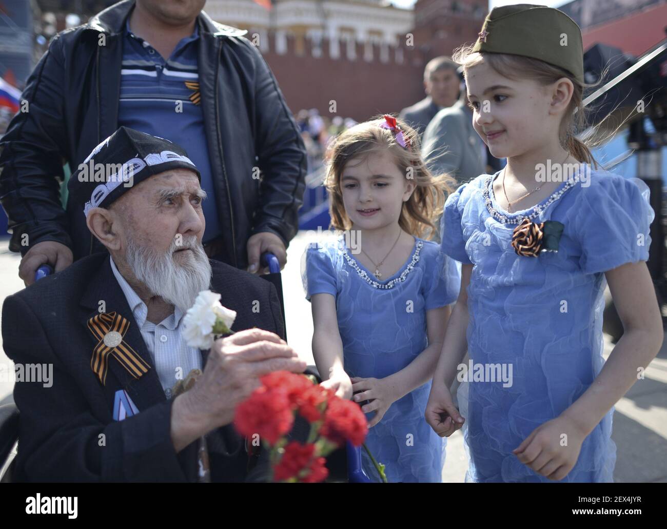 WWII veteran from Uzbekistan receives flowers from two young girls during 'Immortal Regiment ...
