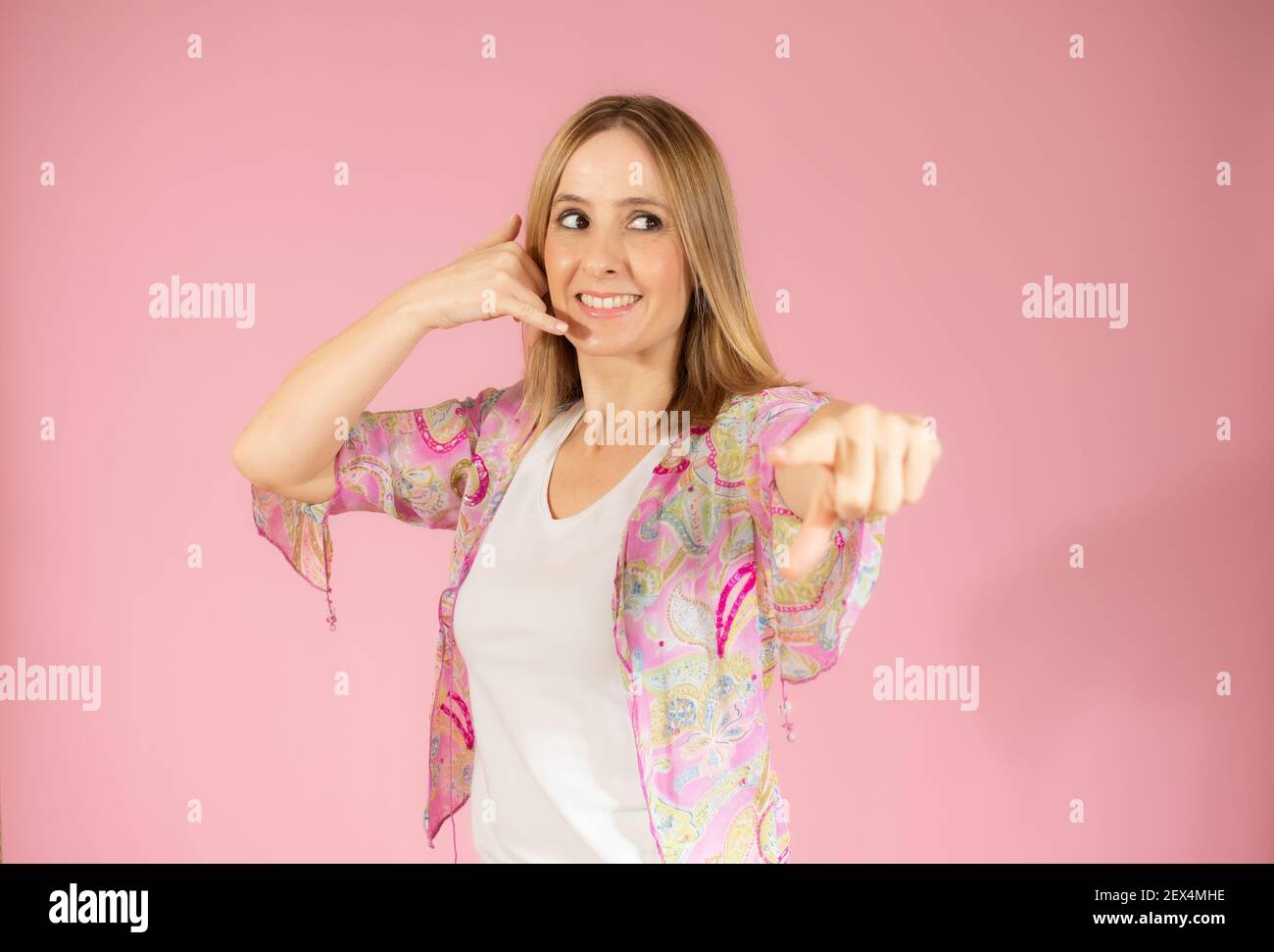 Young woman over isolated pink background making phone gesture. Call me ...