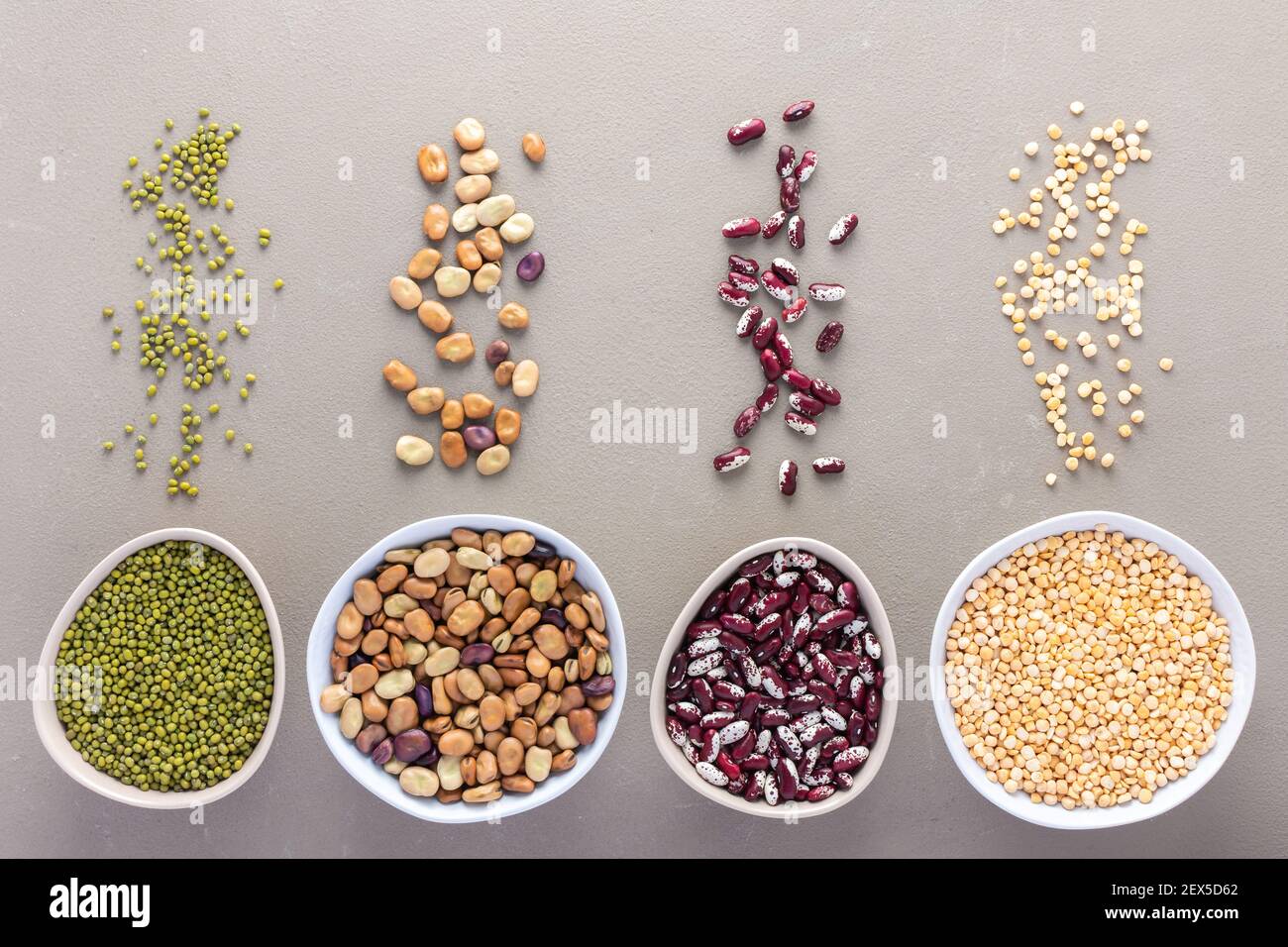 Different types of legumes in bowls and scattered in the background ...
