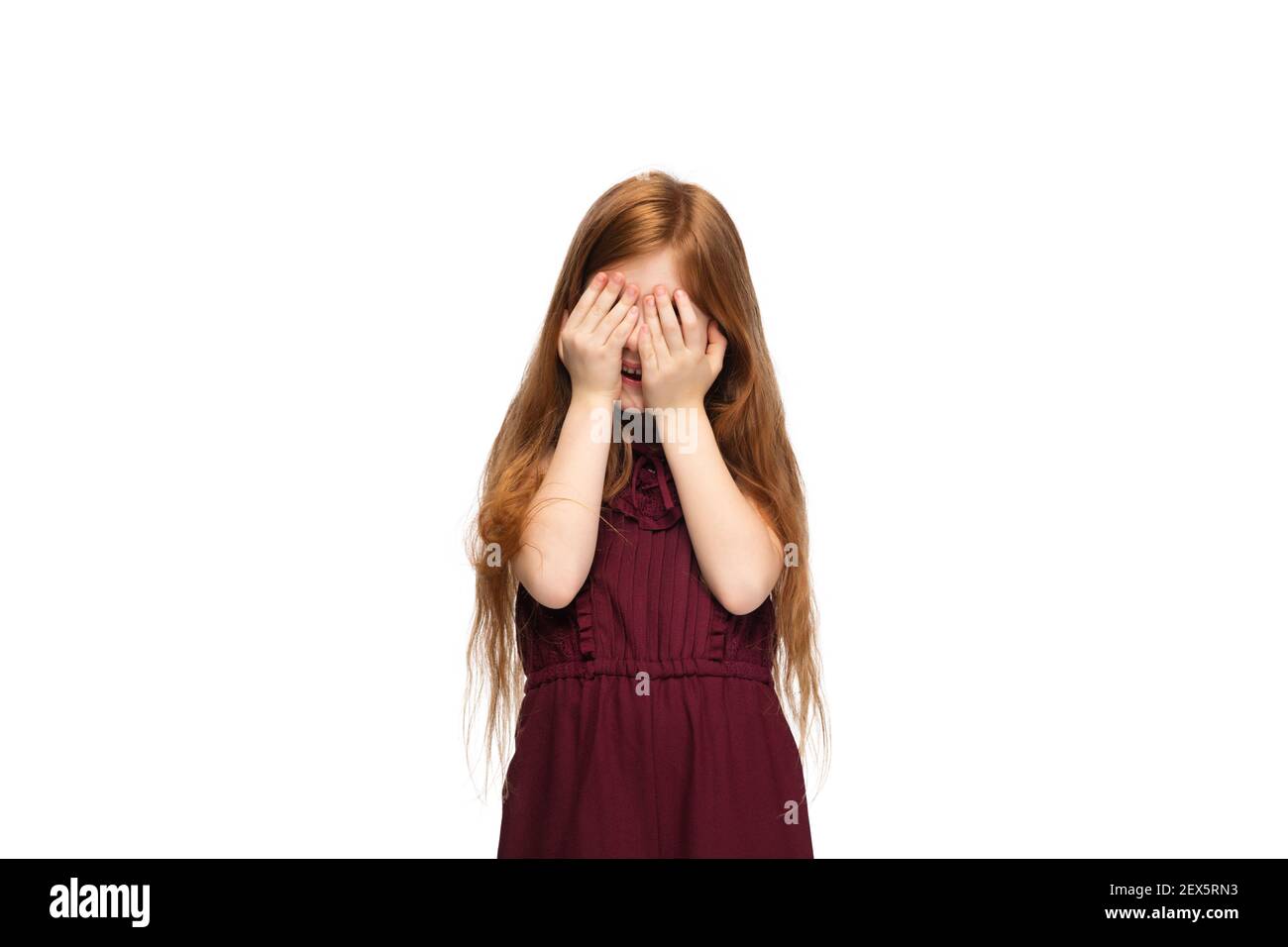 Hiding face with hands. Happy, smiley little caucasian girl on white ...