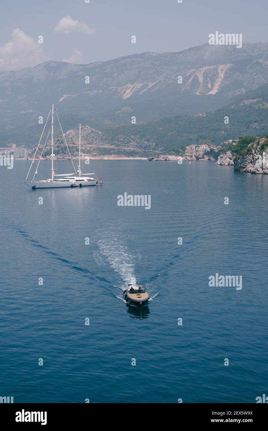 A luxury wooden sports motor boat delivers VIPs from a large white boat ...