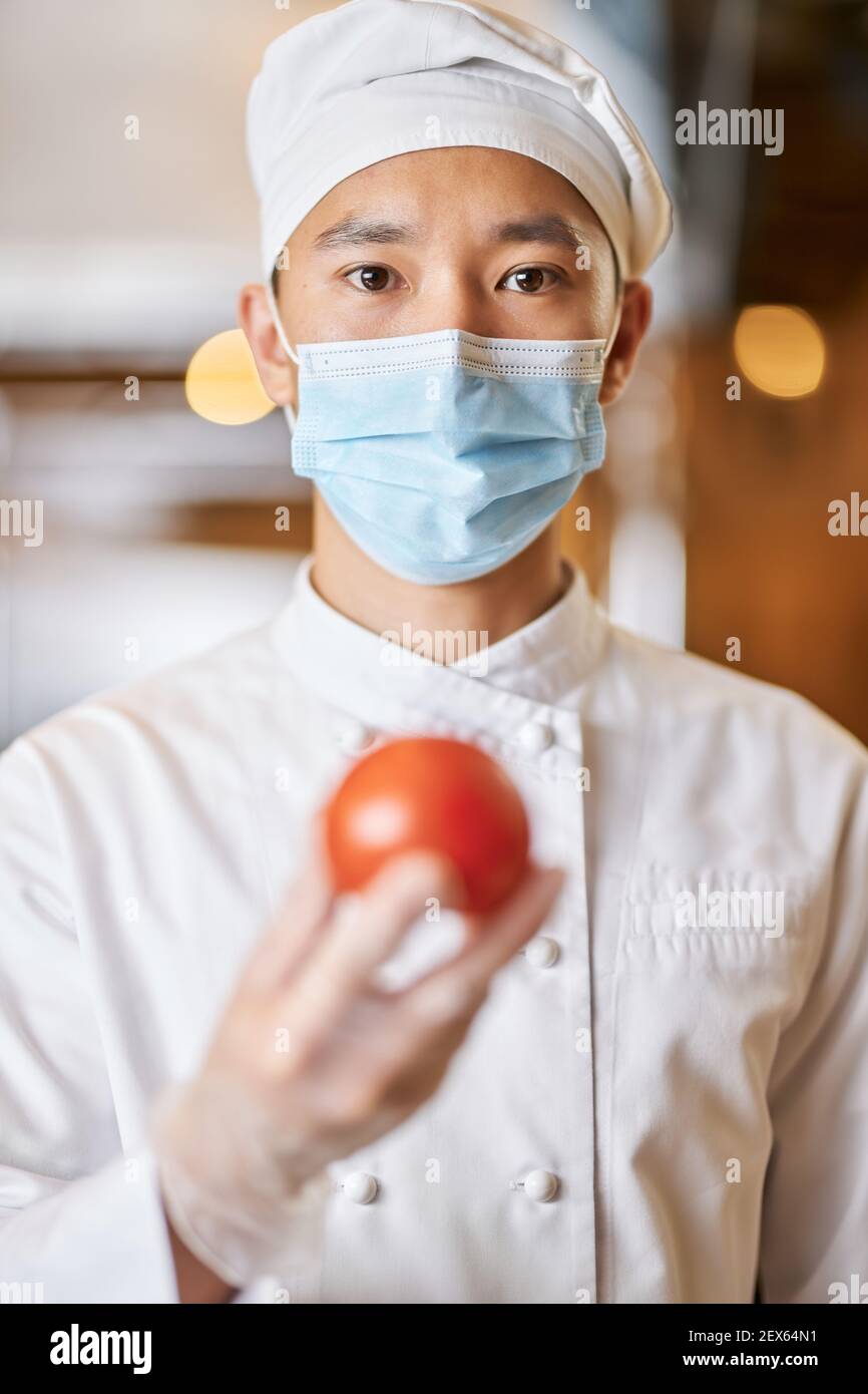 Portrait photo of young Asian chef in protective face mask wearing ...