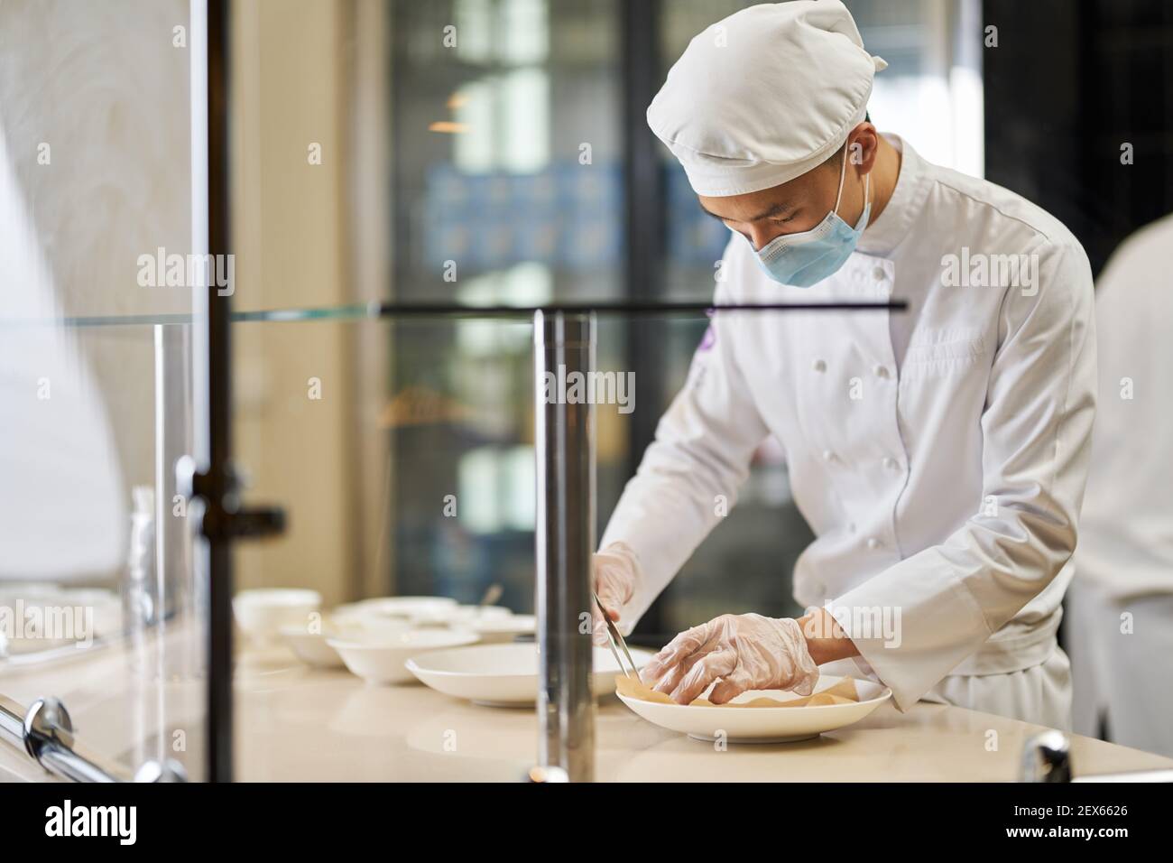 Hard-working professional chef bending over a table while arranging ...