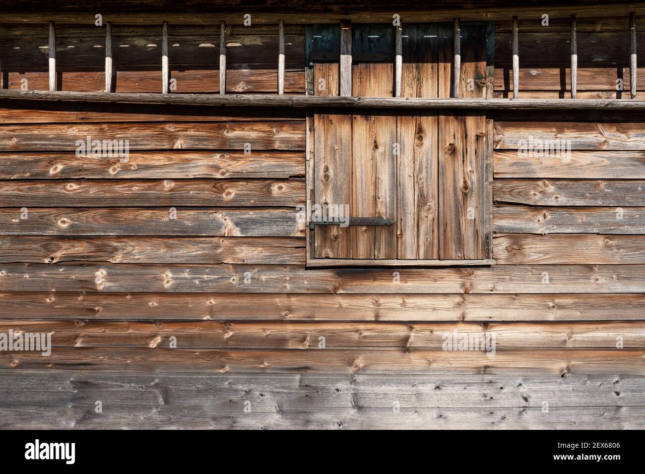Exterior wall of a rustic hut with closed window shutter and ladder ...
