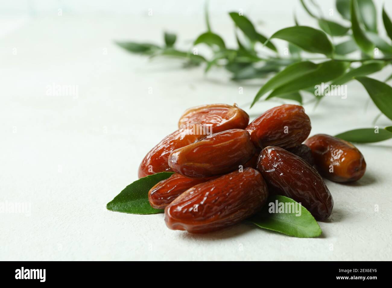 Dried dates and leaves on white textured background Stock Photo - Alamy