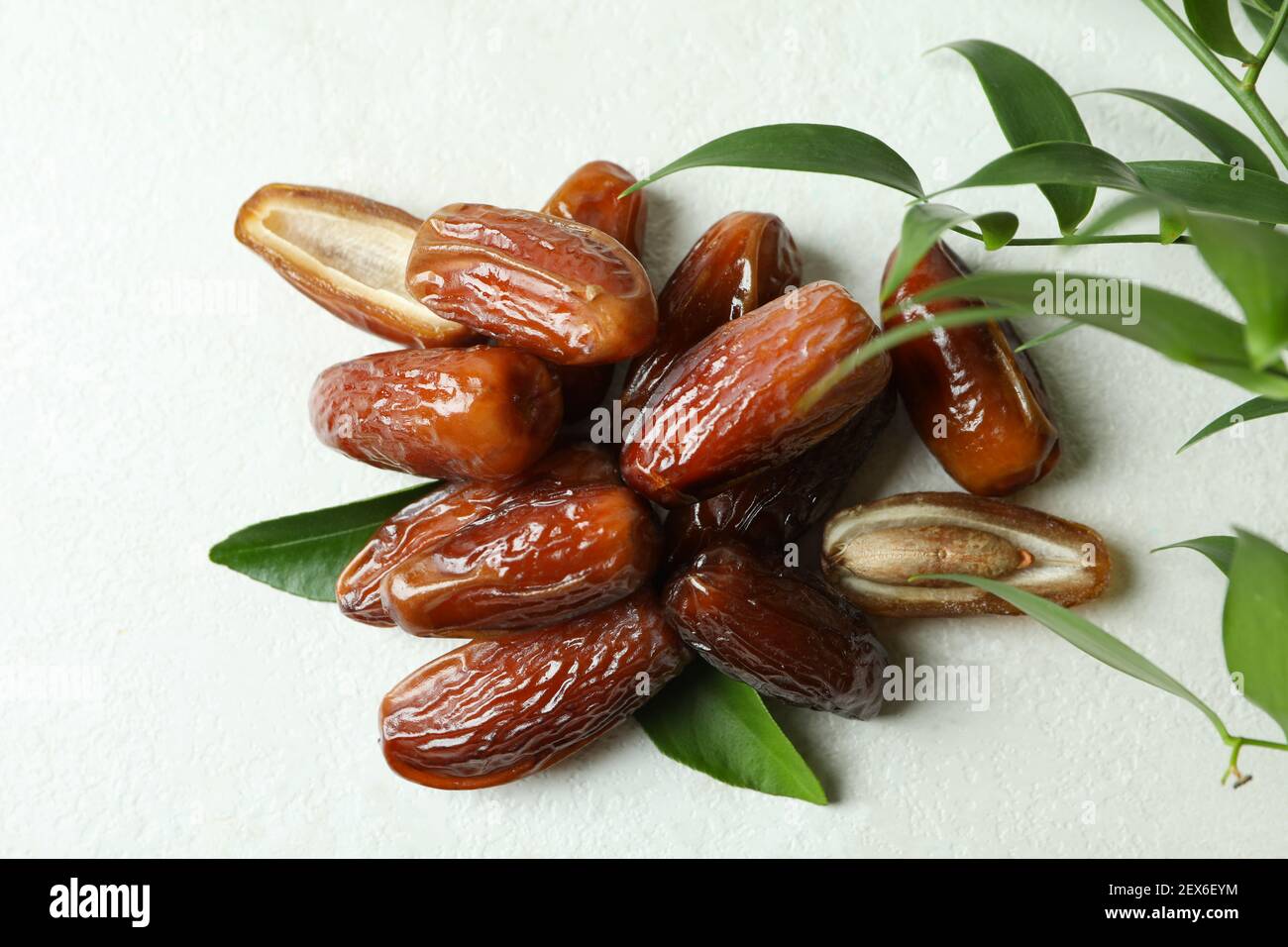 Dried dates and leaves on white textured background Stock Photo - Alamy