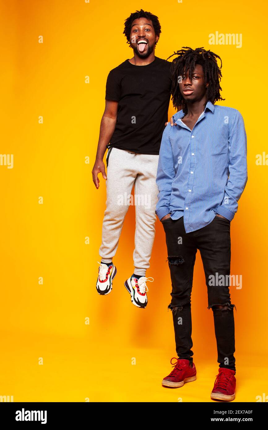 two african american guys posing cheerful together on yellow background ...