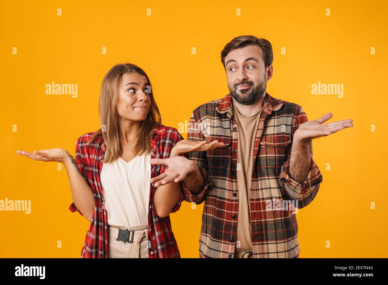 Nice confused couple posing with throwing up hands isolated over yellow ...