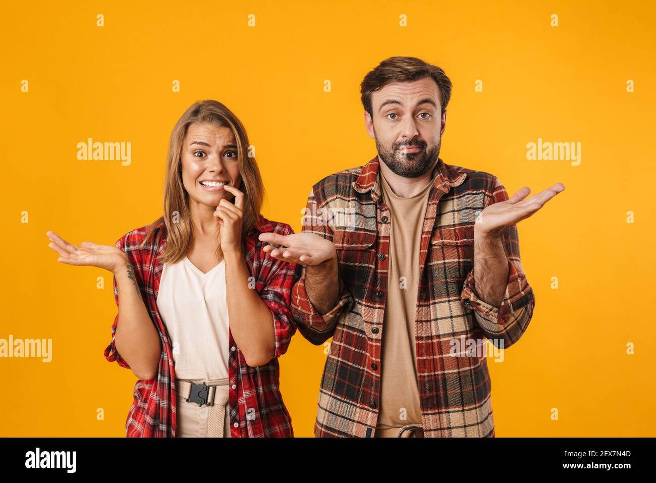 Nice confused couple posing with throwing up hands isolated over yellow ...