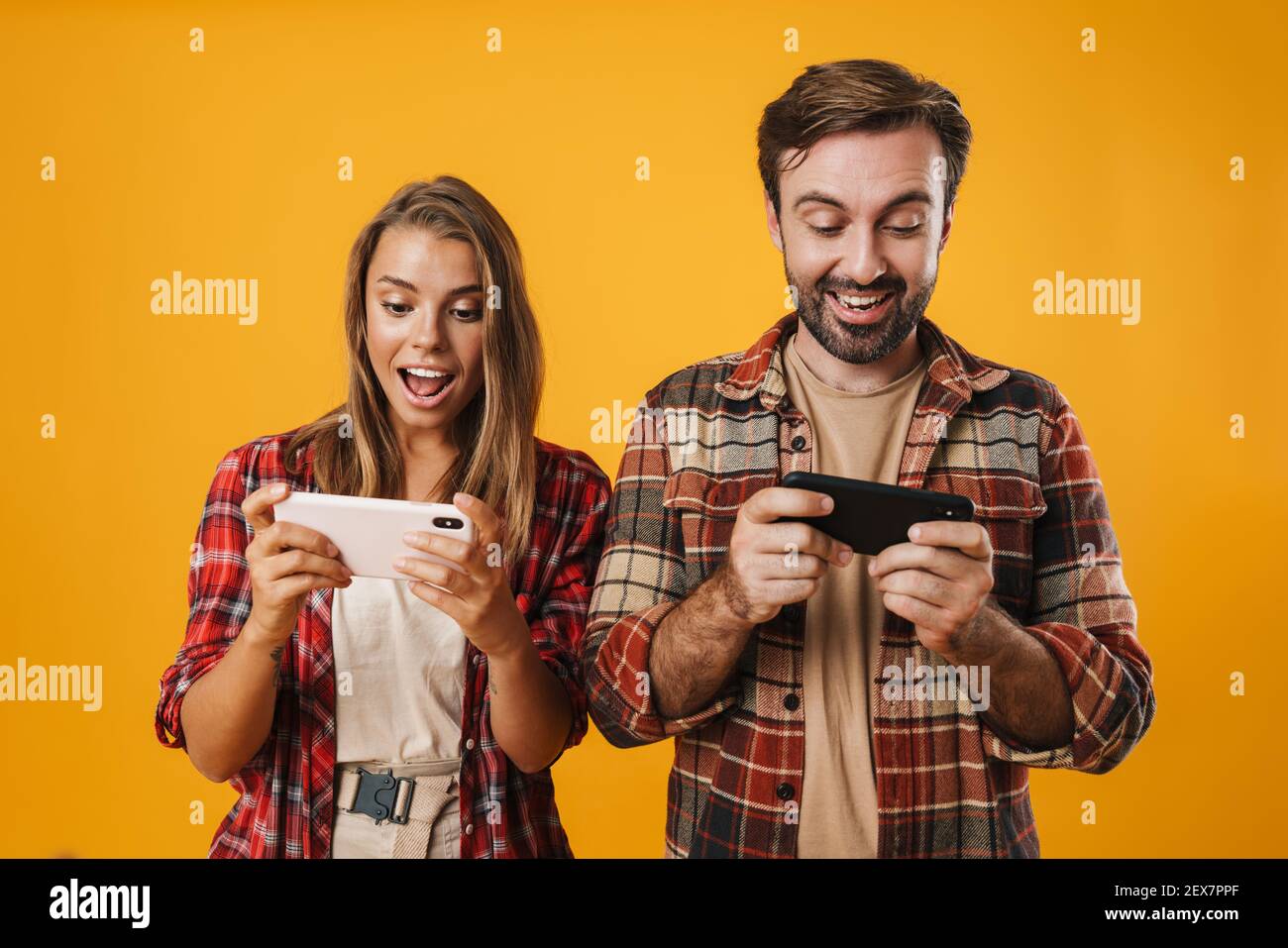 Excited charming couple playing video game on mobile phones isolated ...