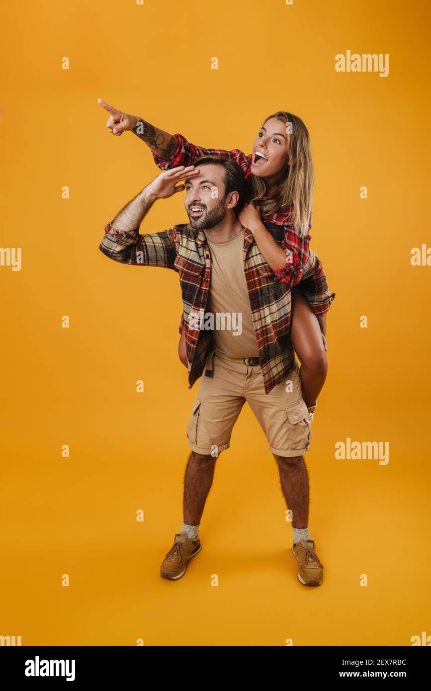 Happy unshaven man piggyback riding his funny girlfriend isolated over ...