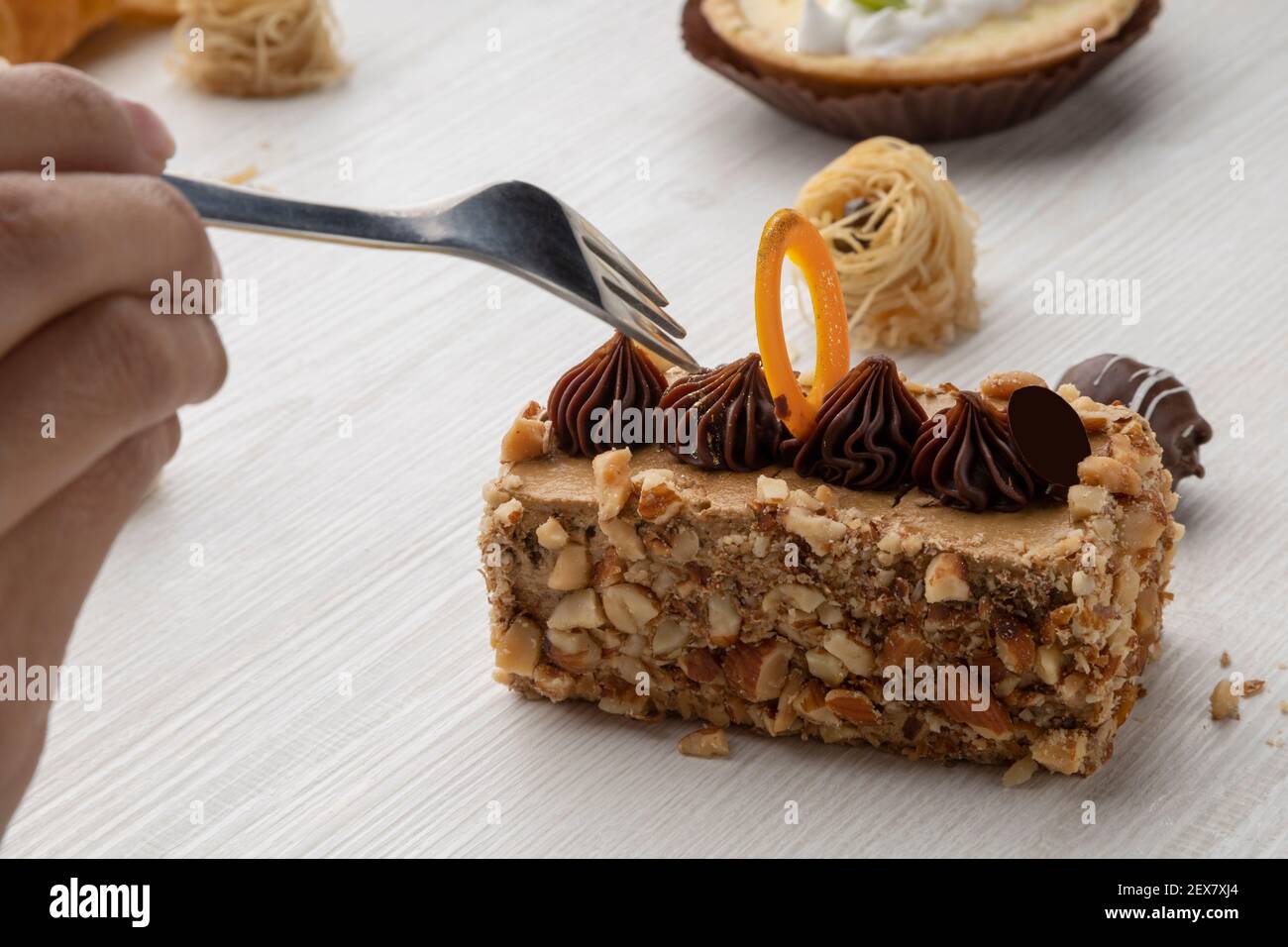 hand with fork cutting a piece of cake filled with walnut with ...